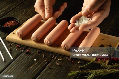 요리사는 굽기 전에 생고기 소시지를 소금에 절입니다 향신료로 부엌 테이블에 튀긴 뮌헨 소시지 요리의 개념 검정색 배경에 대한 스톡 사진 및 기타 이미지 Istock