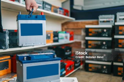 흰색 표면의 다른 배터리 위에 파란색 손잡이를 잡고 있는 사람 배경에 보이는 자동차 배터리와 도구가 있는 선반 개인 장식품에 대한 스톡 사진 및 기타 이미지 Istock