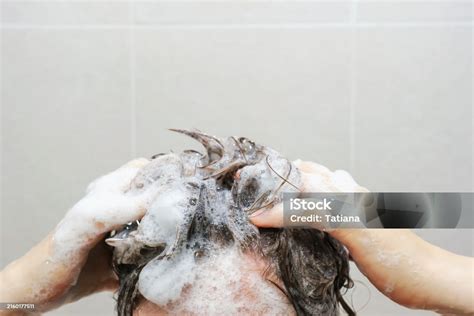 여자는 회색 타일 배경 정면에서 샴푸로 머리를 감고 있습니다 30 34세에 대한 스톡 사진 및 기타 이미지 30 34세