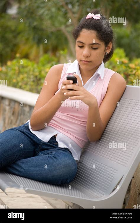 A Young Latina Teenager Sends A Text Messageemail By A Mobile Phone