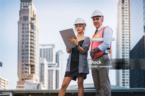 두 명의 만족한 엔지니어가 도시 배경으로 작업하는 현장 건물에 대한 건설을 상담합니다 팀워크 컨셉 가리키기에 대한 스톡 사진 및 기타 이미지 Istock