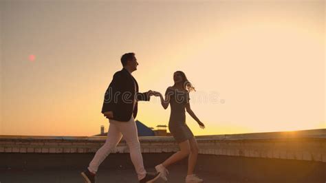 Los Amantes Del Deporte Se RÃen Corriendo En El Techo Del Edificio Al Atardecer En El Fondo De