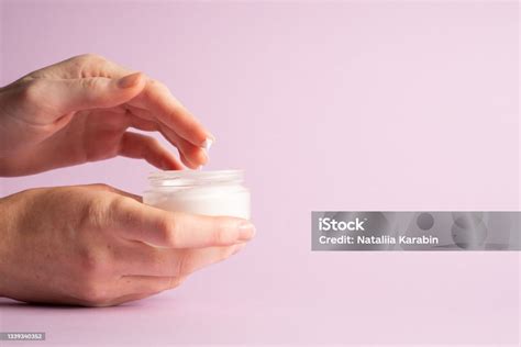 핸드 홀딩 크림 항아리 보라색 배경에 얼굴 크림을 들고 손을 잡고 클로즈업 용기에 모이스처라이저 측면 보기 개념에 대한 스톡