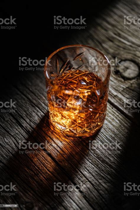 소박한 나무 테이블 위의 유리잔에 얼음이나 브랜디를 곁들인 위스키 유리잔에 얼음을 넣은 위스키 유리에 위스키 또는 코냑 선택적 초점 스톡 사진 0명에 대한 스톡 사진 및