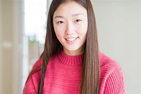 얼굴에 심각한 표정으로 편안한 분홍색 스웨터를 입고 아름 다운 아시아 여자 교차 팔로 간단 하 고 자연 스러운 갈색 머리에 대한