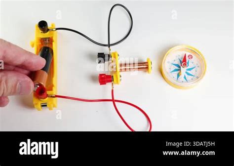 Hands Demonstrate Magnetic Forces Using An Electromagnet And Compass