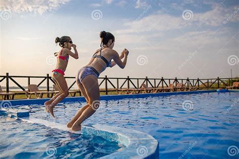 Zwei Mädchen Springen Im Sommerurlaub Bei Sonnenuntergang in Den Pool Stockbild - Bild von leute ...