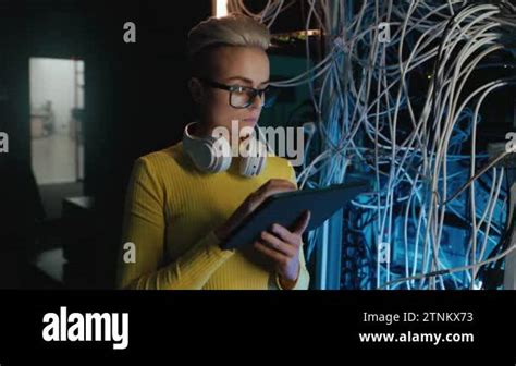 IT Woman Working At Server Room Using Mobile Tablet Maintaining Internet Connection And