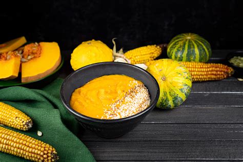 녹색 직물 호박 씨앗 옥수수의 조각을 사용하여 어두운 나무 배경에 검은 색 세라미 접시에 호박 크림 수프 평평한 평신도 복사