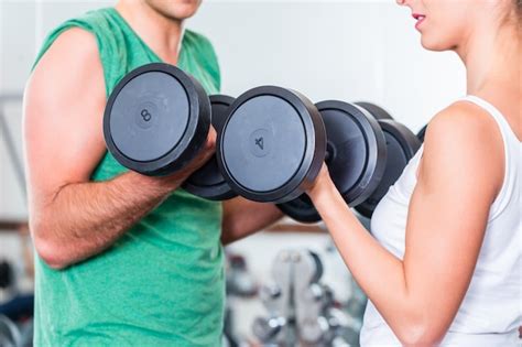 Premium Photo Young Couple In Gym Lifting Dumbbell