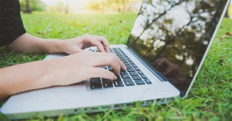 열린 노트북으로 푸른 잔디에 젊은 아시아 여자의 다리 키보드에 소녀의 손 원격 학습 개념입니다 공원에서 노트북으로 일하는 행복한 힙스터 젊은 아시아 여성 야외에서