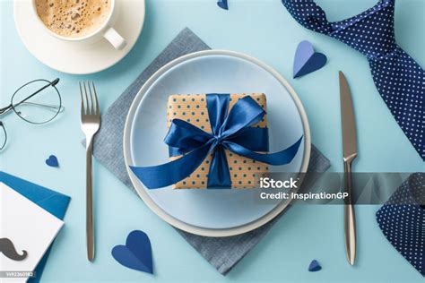 파스텔 블루 배경에 접시 커피 머그잔 수저 냅킨 리본 리본 넥타이 안경 우편 및 하트가 있는 선물 상자가 있는 멋진 아버지의 날 테이블 배열 0명에 대한 스톡 사진 및 기타