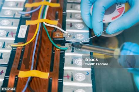 기술자는 납땜 인두를 사용하여 리튬 이온 충전식 배터리의 금속 및 와이어를 납땜합니다 리튬 이온 배터리의 수리 모듈 엔지니어 손은 납땜 인두와 주석 리드를 납땜 전자 보드로