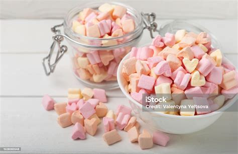 하얀 질감의 나무에 그릇과 항아리에 담긴 다양한 마시멜로 흰색과 과일 마시멜로 간식으로 과자와 간식 사탕을 클로즈업하여 씹는다