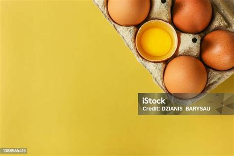 신선한 갈색 계란과 노른자가 있는 깨진 달걀은 밝은 노란색 배경에 재활용 된 종이 에코 트레이에 텍스트 복사 공간을 위한 공간이 있습니다 0명에 대한 스톡 사진 및 기타