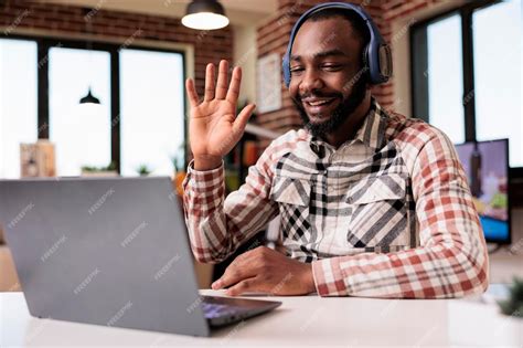 Free Photo Programmer With Wireless Headphones In Video Conference Waving Hello At Client