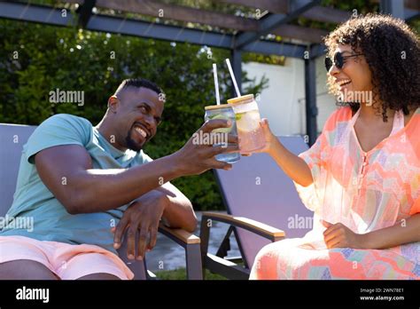 Casually Dressed Duo Enjoys Sunny Outdoor Drinks Sharing Joy Stock