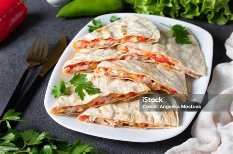 회색 배경에 흰색 접시에 베이컨 닭고기 치즈 및 후추를 곁들인 Tortilla의 멕시코 스낵 퀘사 딜라 퀘사디아에 대한 스톡