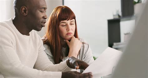 예산 서류 및 재정을 위해 가정의 거실에서 인종 간 부부와 함께 돈 투자 또는 저축 남자와 여자가 자산 계획을 위해 종이에 정보를 읽습니다 2명에 대한 스톡 사진 및 기타