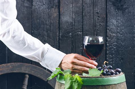 맨 손으로 레드 와인의 유리를 보유 하고있다 나무 통에 와인 번 트 검은 나무 배경입니다 빈티지입니다 Copyspace 텍스트에 대 한입니다 포도 그리고 녹색 덩굴입니다