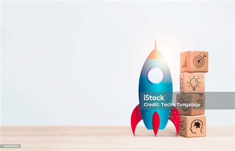 리더십 컨셉을 위한 성장 성공 프로세스를 갖춘 비즈니스 스타트업 나무 큐브 블록 옆에 있는 로켓은 복사 공간이 있는 흰색 배경의 나무 테이블에 비즈니스 전략 아이콘이 쌓여