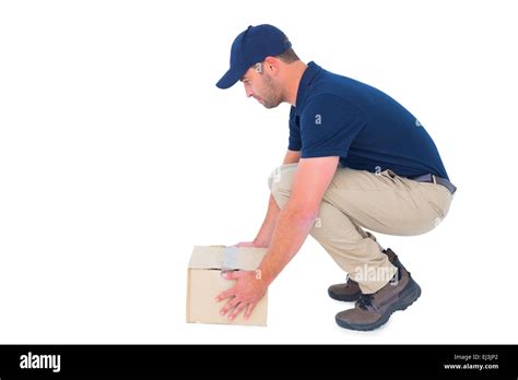 Delivery Man Crouching While Picking Cardboard Box Stock Photo Alamy