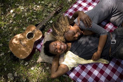 Couple Lying In Each Others Arms On A Picnic Blanket Stock Image