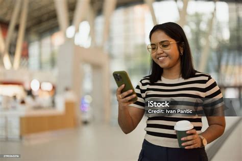전화를 사용하여 웃는 여자와 현대적인 실내 환경에서 커피 컵을 들고 20 29세에 대한 스톡 사진 및 기타 이미지 20 29