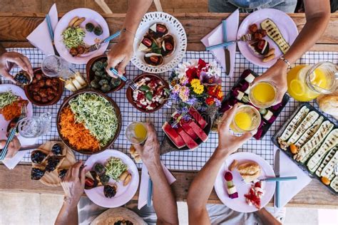 Vertical Top View Of Friends Eating Together On A Wooden Table Full Of