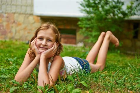 La Fille De Douze Ans Se Trouve Sur L Herbe Et Le Sourire Photo Stock