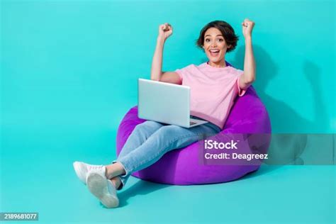 놀란 아가씨 앉아 가방 의자 사용 넷북 즐기다 축하 팔 올리기 손 주먹 예 청록색 배경에 고립 된 빈 공간 25 29세에 대한 스톡 사진 및 기타 이미지 Istock