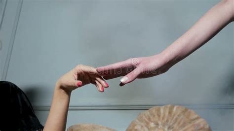 Two Girls Stand In Light Coats In The Studio And Lean Their Fingers