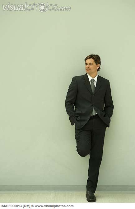 Businessman Standing On One Leg Leaning Against Wall With Hands In