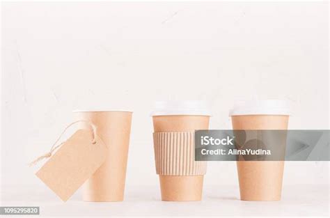 커피 포장 이랑흰색 나무 보드 커피숍 인테리어에 흰색 모자 컵 홀더 및 빈 레이블 3 갈색 공예 종이 컵의 설정 브랜드 정체성 광고 디자인에 대 한 현대 우아한 개념 3가지