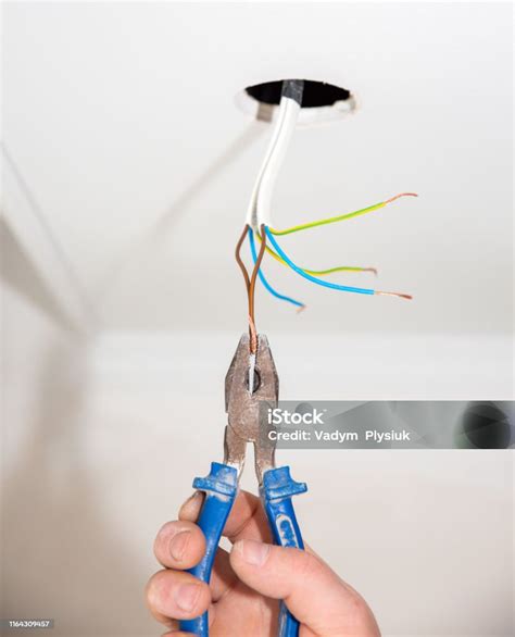 남자는 그의 손에 펜치를 들고있다 전구용 전기 절연체 유지 보수 수리를위한 접착제 테이프는 평면에서 작동합니다 실내 복원 전기 연료 및 전력 생산에 대한 스톡 사진 및 기타