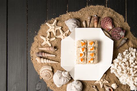 바다 조개와 모래 배경에 배달 테이크 아웃 상자에 아시아 초밥의 측면 보기 참깨 일본 마요네즈 붉은 캐비어를 곁들인 롤 Tamagoyaki에 대한 스톡 사진 및 기타 이미지