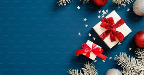 빨간 리본 활 공 장식 및 색종이가 있는 진한 파란색 배경에 소나무 가지가 있는 흰색 선물 상자 크리스마스 선물 개념입니다 플랫 레이 평면도 사진