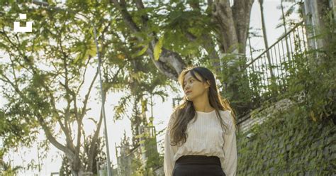 흰색 긴팔 셔츠와 검은 치마를 입은 여자가 낮 동안 회색 콘크리트 도로에 서 있다 사진 Unsplash의 무료 Ảo Lộc 이미지