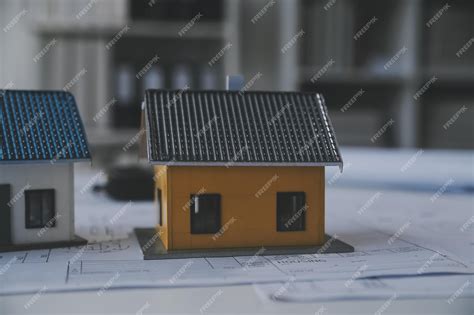 건축 설계자 및 건축가 작업 개념을 위해 건물 건설 계획을 위해 색 배경에 고립 된 도구 및 블루프린트 롤을 그린 책상 위의 집의 건축 모델 프리미엄 사진