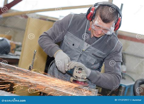 Young Manual Worker Using Grinder On Metal In Factory Stock Image