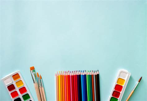 주황색 더미와 나무 질감이 있는 3개의 라이트 베이지 색 브러시가 있는 수평 클로즈업 플랫 레이 컴포지션은 컬러 수채화 페인트 컬러 연필 밝은 파란색 배경에 5개의 구아체