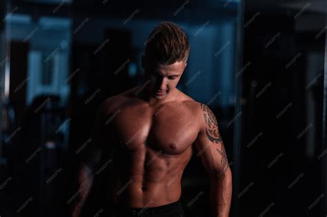 Premium Photo Muscular Bodybuilder Guy Standing On Gym In The Dark