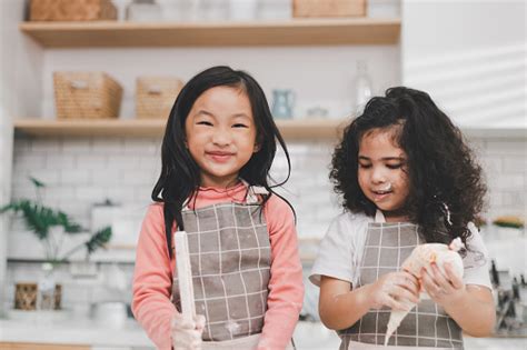 아이들은 부엌에서 요리를 즐깁니다 케이크를 장식하는 행복한 아시아 아이들은 부엌에서 쿠키를 굽습니다 두 명의 귀여운 다양성