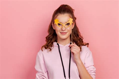 후드에 포니 테일과 귀여운 행복 한 십대 소녀의 초상화 미소와 스틱에 종이 안경을 들고 휴일에 파티 소품을 사용 하 여 재미 기이함에 대한 스톡 사진 및 기타 이미지
