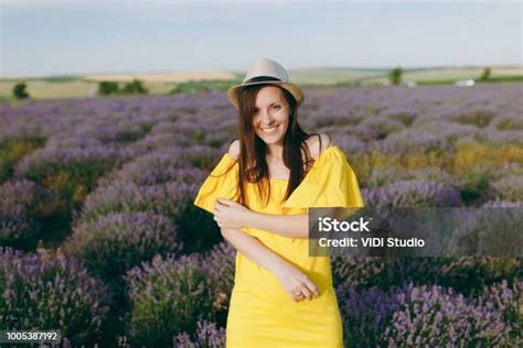 노란색 드레스에 젊은 웃는 아름 다운 여자 보라색 라벤더 꽃 꽃 초원 경기장에서 야외 여름 자연 배경 모자의 초상화 꽃 덤 불 근처 행복 한 여성입니다 라이프 스타일