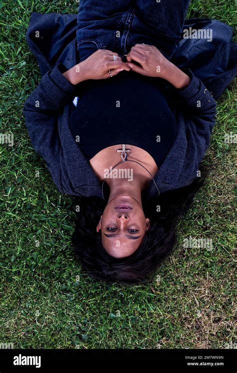 Looking Down On Young Woman Laying On The Grass As She Looks Back Up