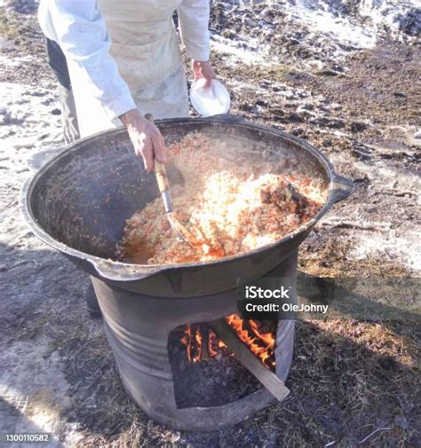 셰프는 스테이크의 가마솥에서 길거리에서 식사를 준비합니다 한 남자가 고기로 밥을 요리합니다 앞치마에 있는 사람이 필라프를 준비합니다 가마솥에 대한 스톡 사진 및 기타 이미지