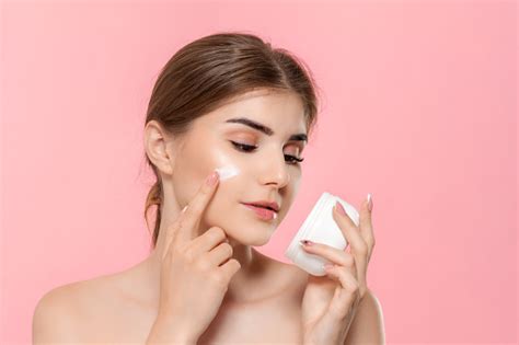 튜브에서 피부에 보습 크림을 적용 하는 아름 다운 여자 모델은 분홍색 배경 위에 격리 된 카메라를 봅니다 미용 및 건강 치료의 개념 갈색 머리에 대한 스톡 사진 및 기타