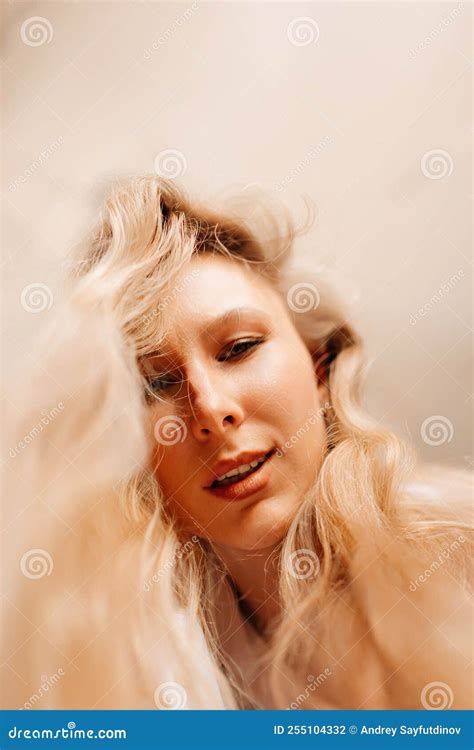 An Attractive Blonde In A White Shirt Looks Down Into The Camera Stock