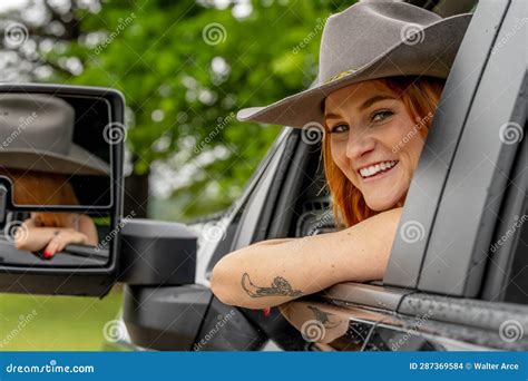 A Lovely Redhead Model Sits In Her Truck While Wearing A Cowboy Hat On